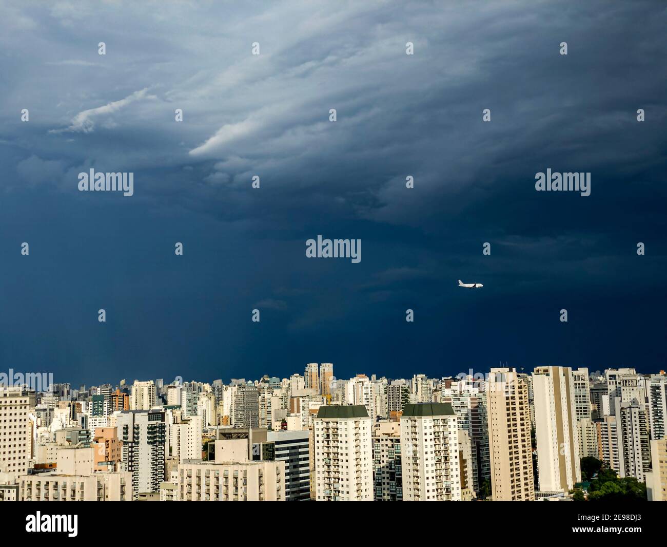 Many buildings, rain clouds, and passing plane Stock Photo - Alamy