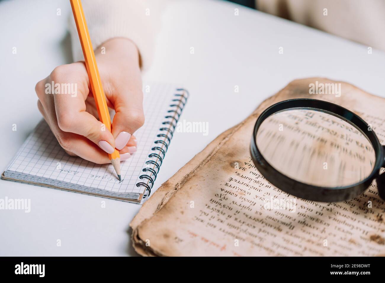 Researcher examines antique book with magnifying glass. Scientific ...