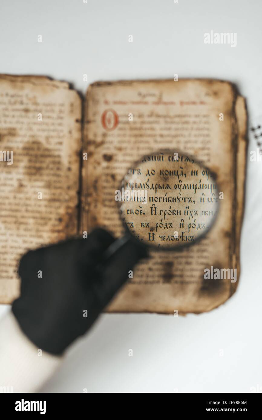 Historian scientist in gloves reading antique book with magnifying ...