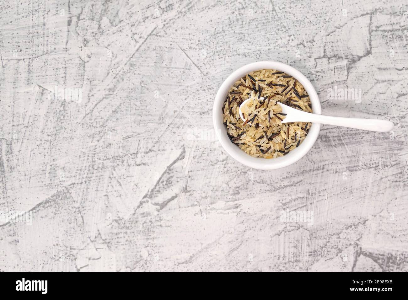 Mixed rice grains. Mixed rice in white plate and spoon on white stone ...