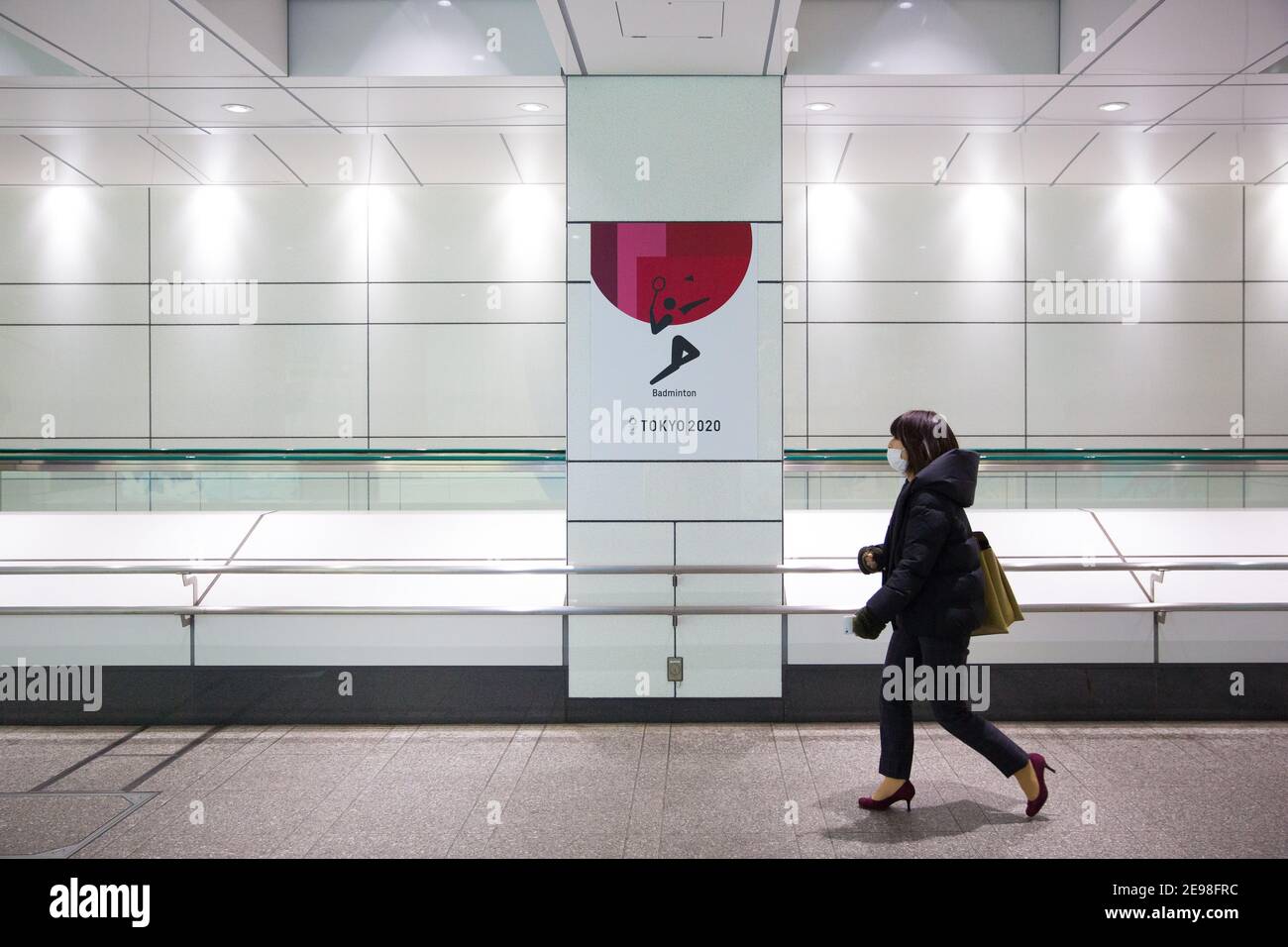 A woman wearing a mask walks past Tokyo 2020 Olympic Games posters ...