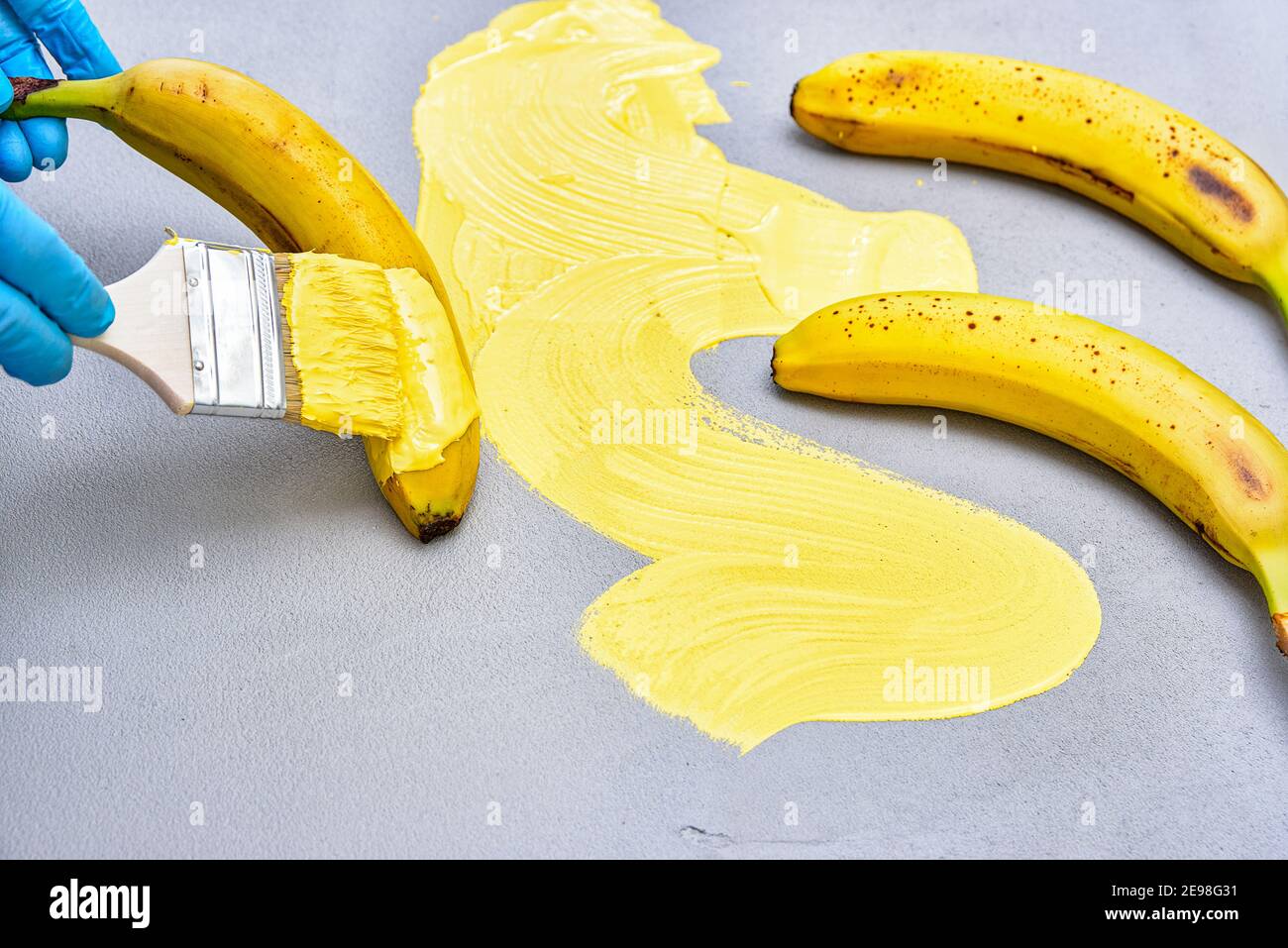 man in blue gloves painting banana with brush with yellow paint Stock ...
