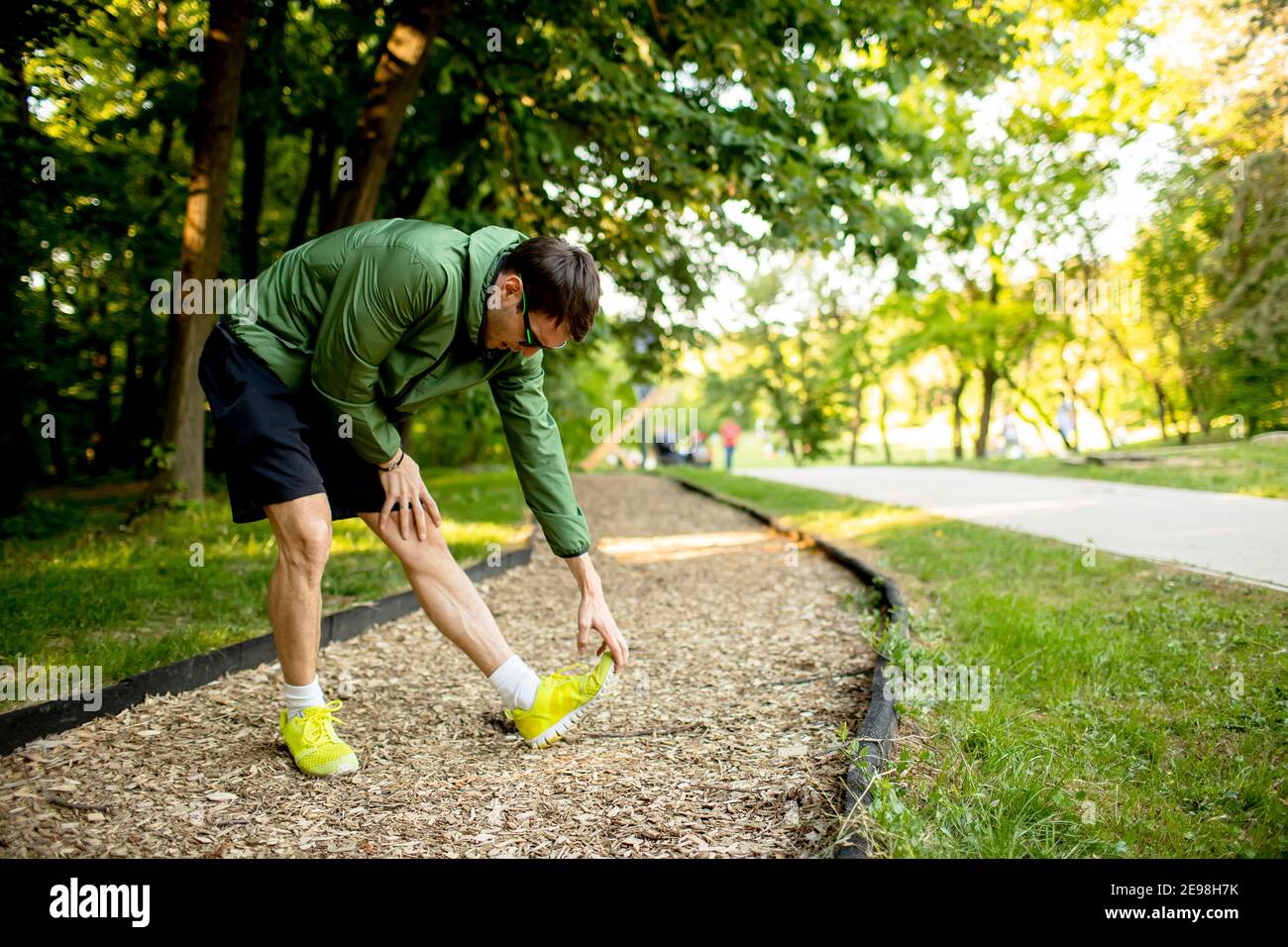 Handsome athletic young man having a break while doing workout in sunny ...