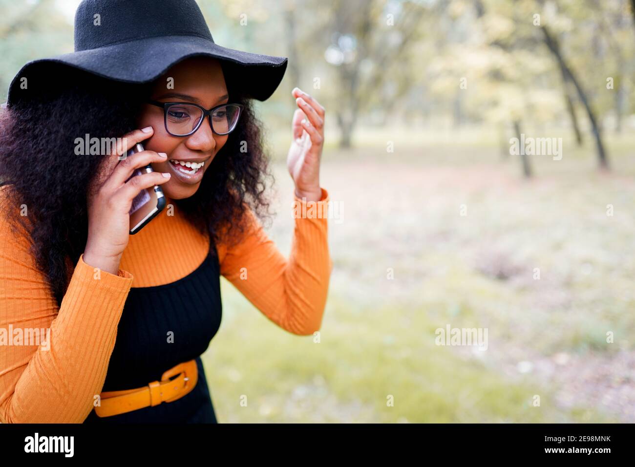 Black woman talking on phone outdoors in the park Stock Photo - Alamy