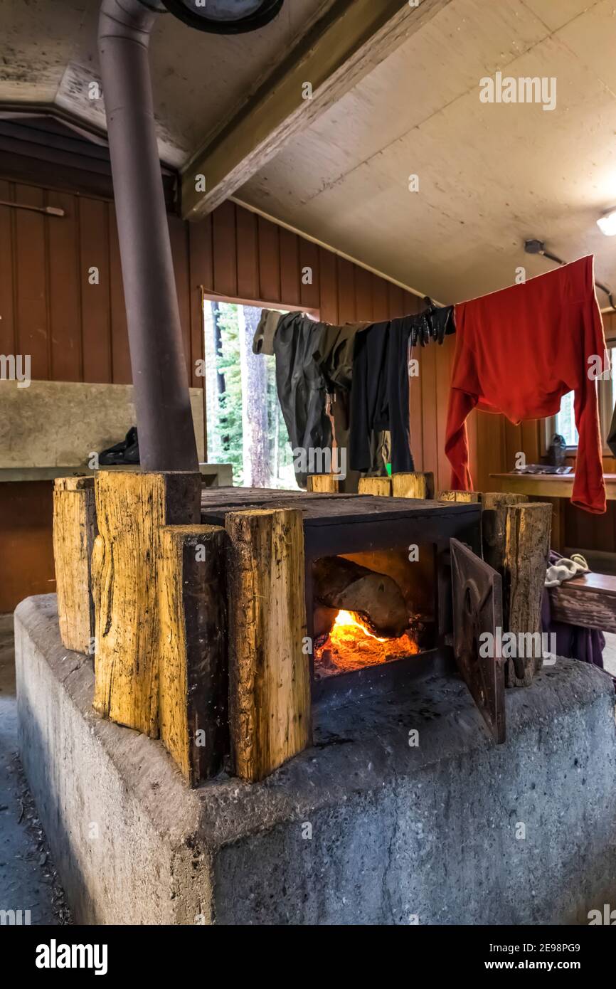 Hikers drying clothing by a wood fire in campground shelter in Banff ...