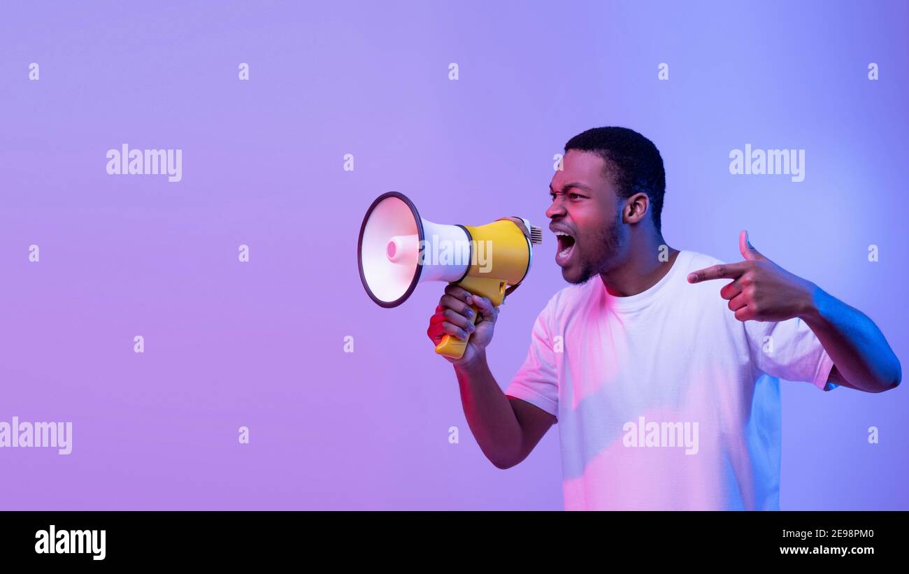 Full length portrait of aggressive young man shouting using megaphone ...