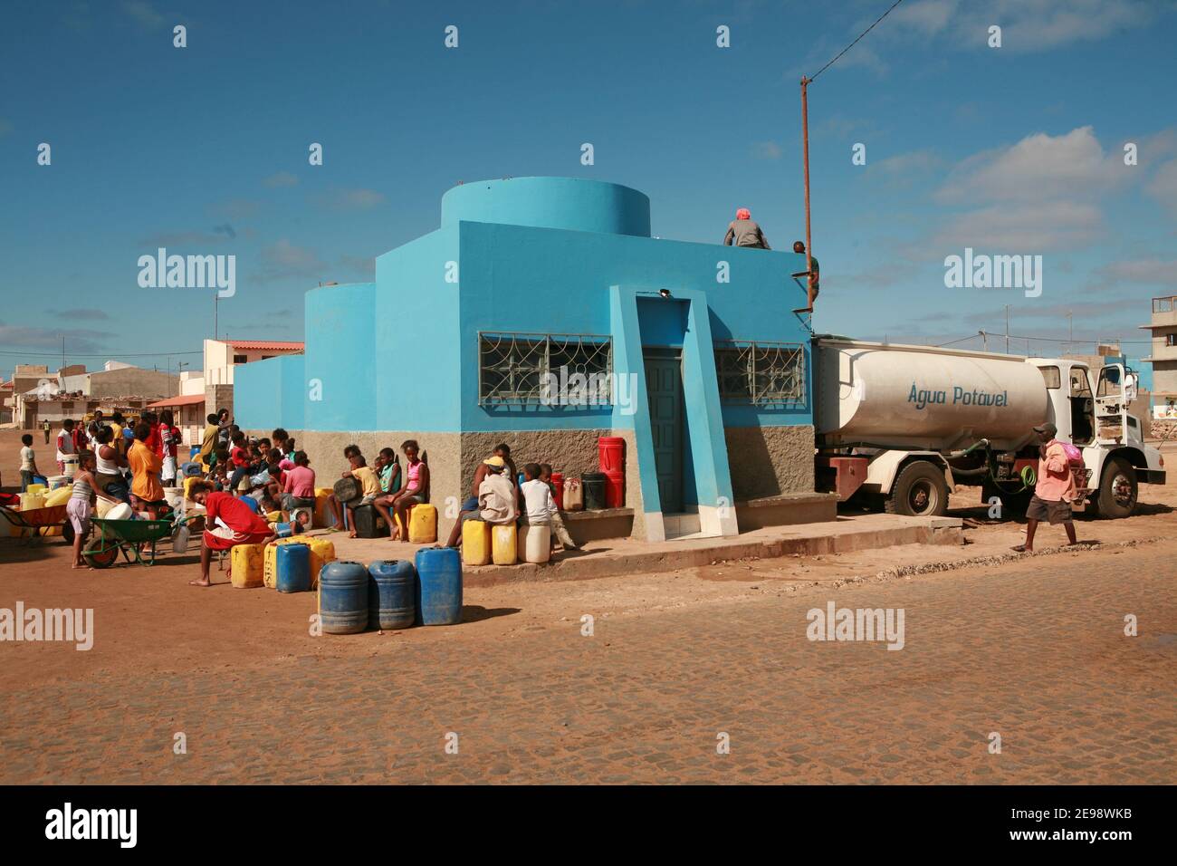 The villagers wait their turn with the canisters to get water at the ...