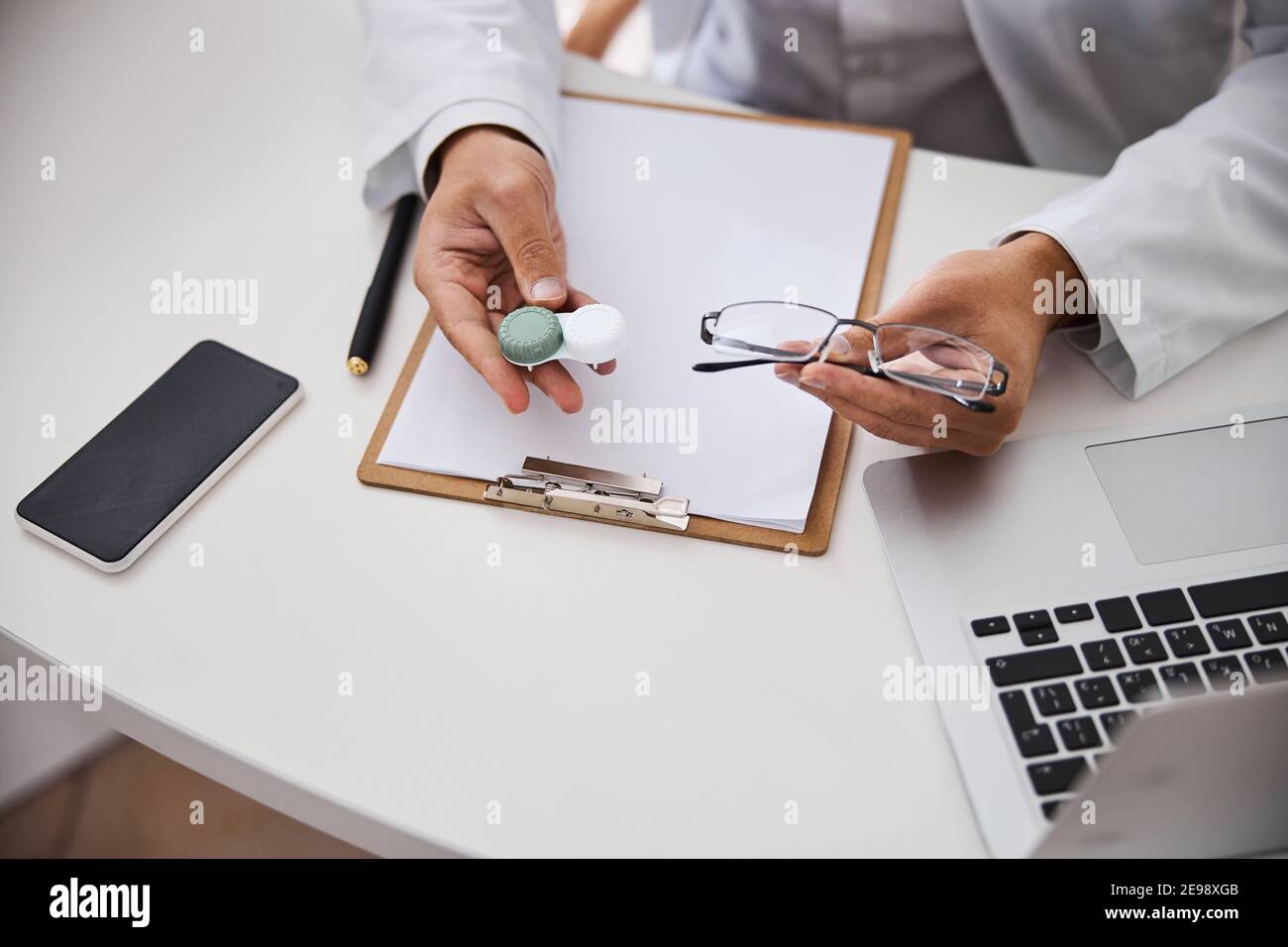Optician in a lab coat sitting at his desk Stock Photo - Alamy