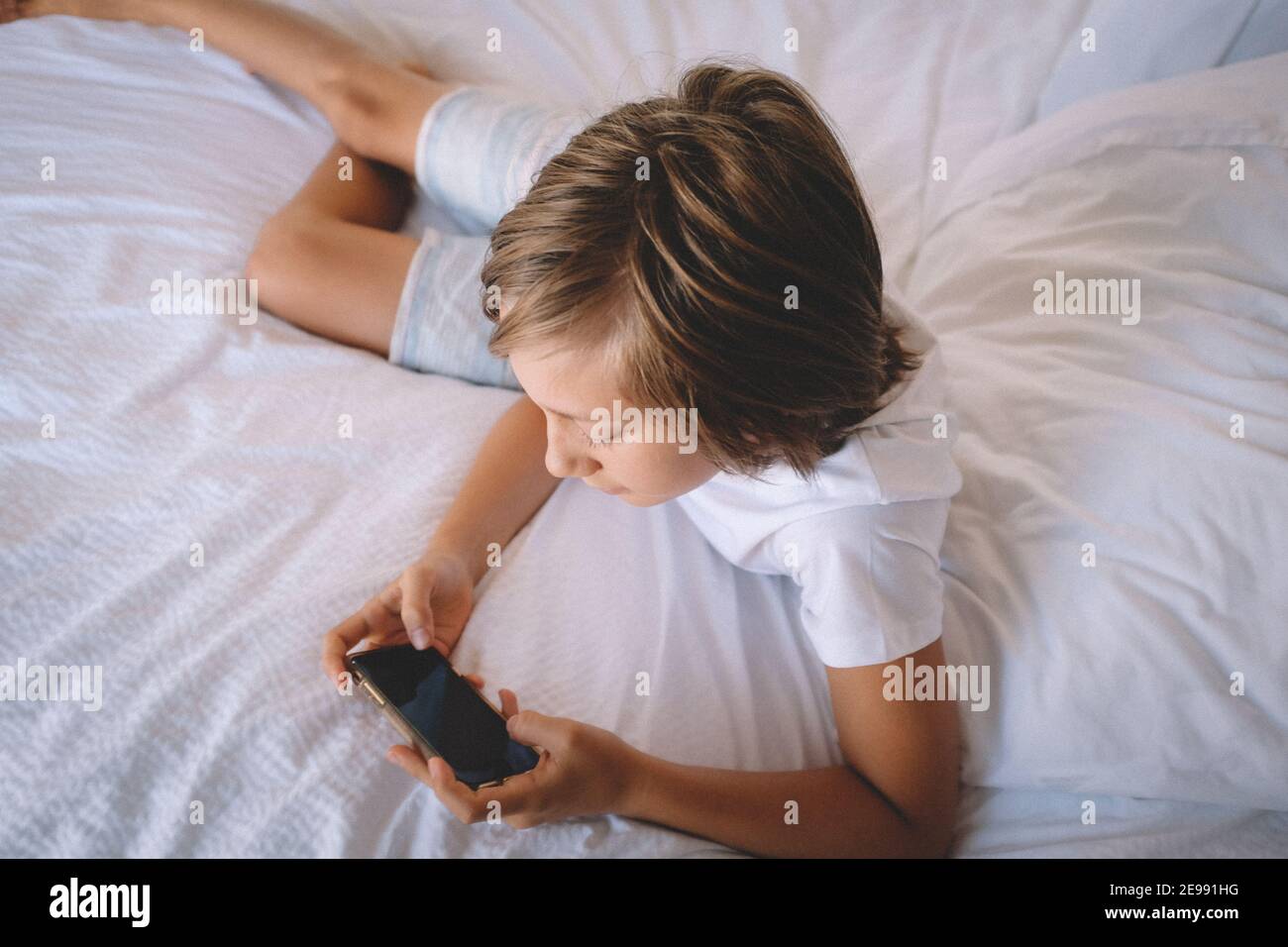 Boy in White Checks on his phone from a hotel Room Bed Stock Photo - Alamy