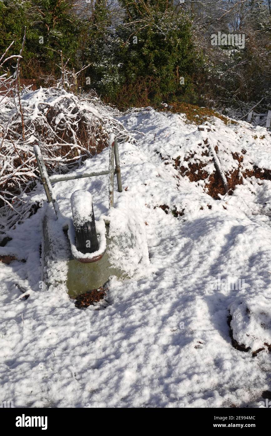 An upturned wheelbarrow lying in the snow on a pile of snow covered ...
