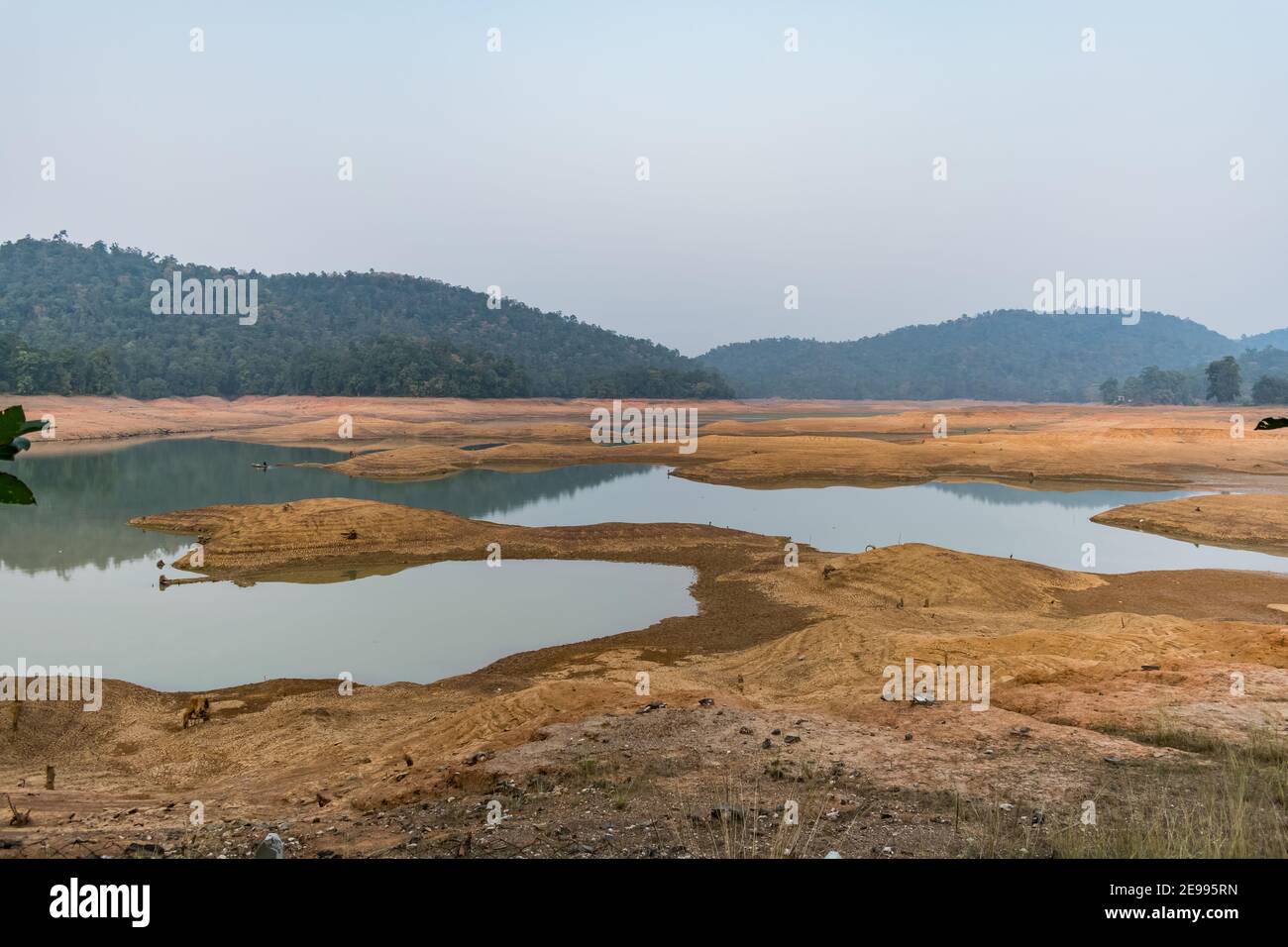 An rural indian small lake have very less water with greenery mountain ...