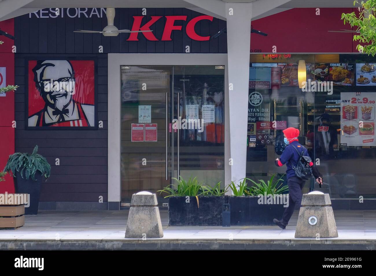 A lady wearing a face mask walks past the KFC restaurant in Putrajaya ...