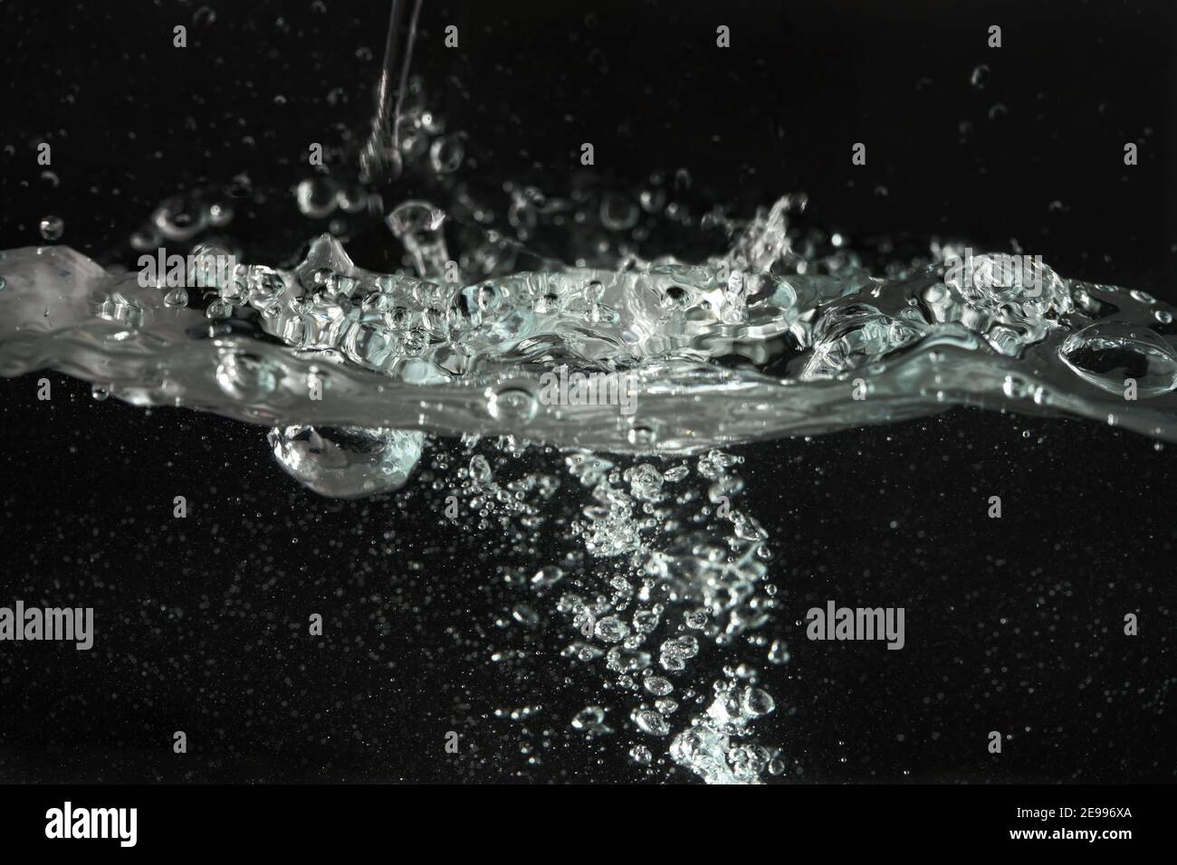 Water splashing as it's poured into aquarium tank, black background ...