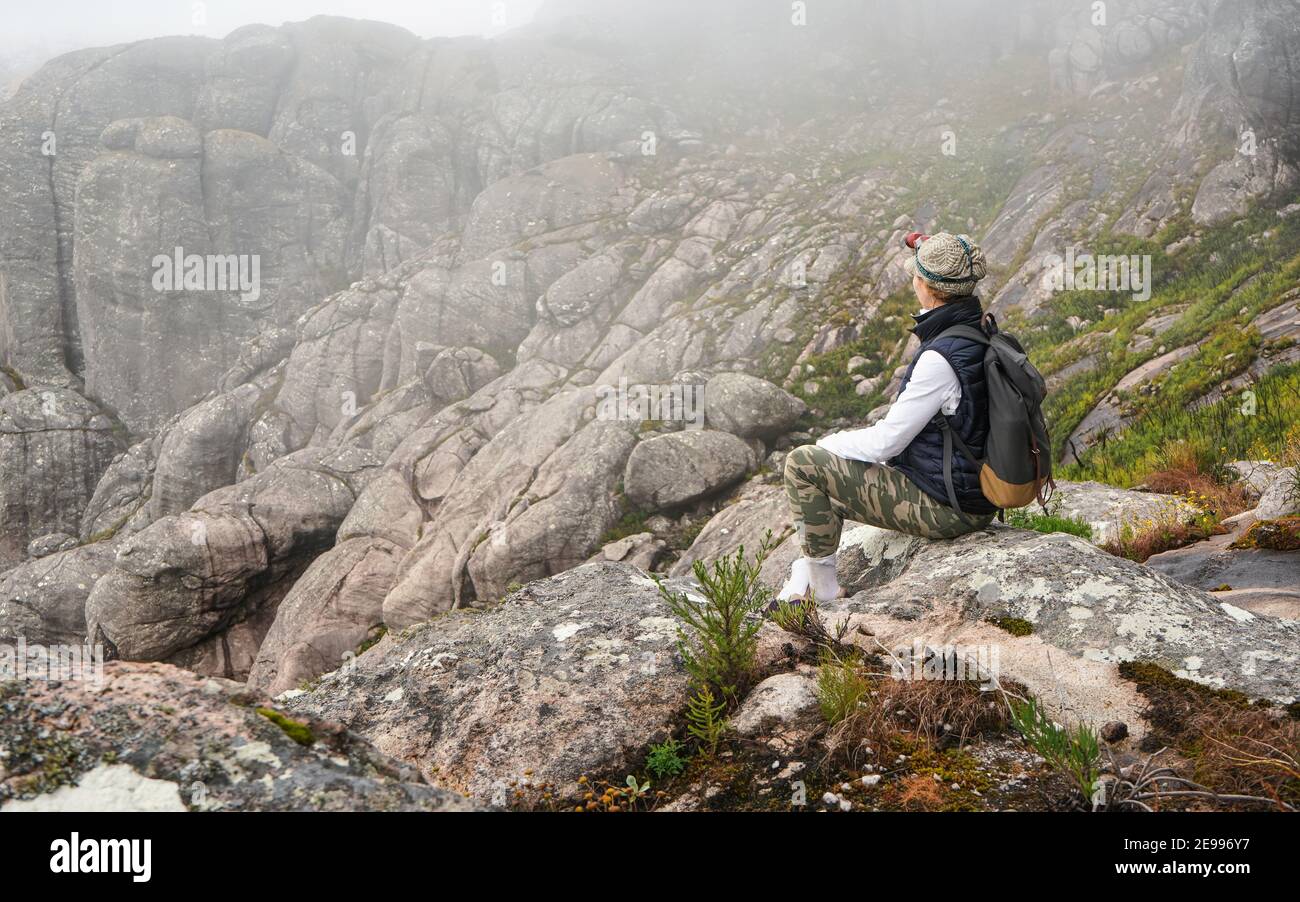 Young woman in sports clothing sitting on rocks enjoying the scenery of ...