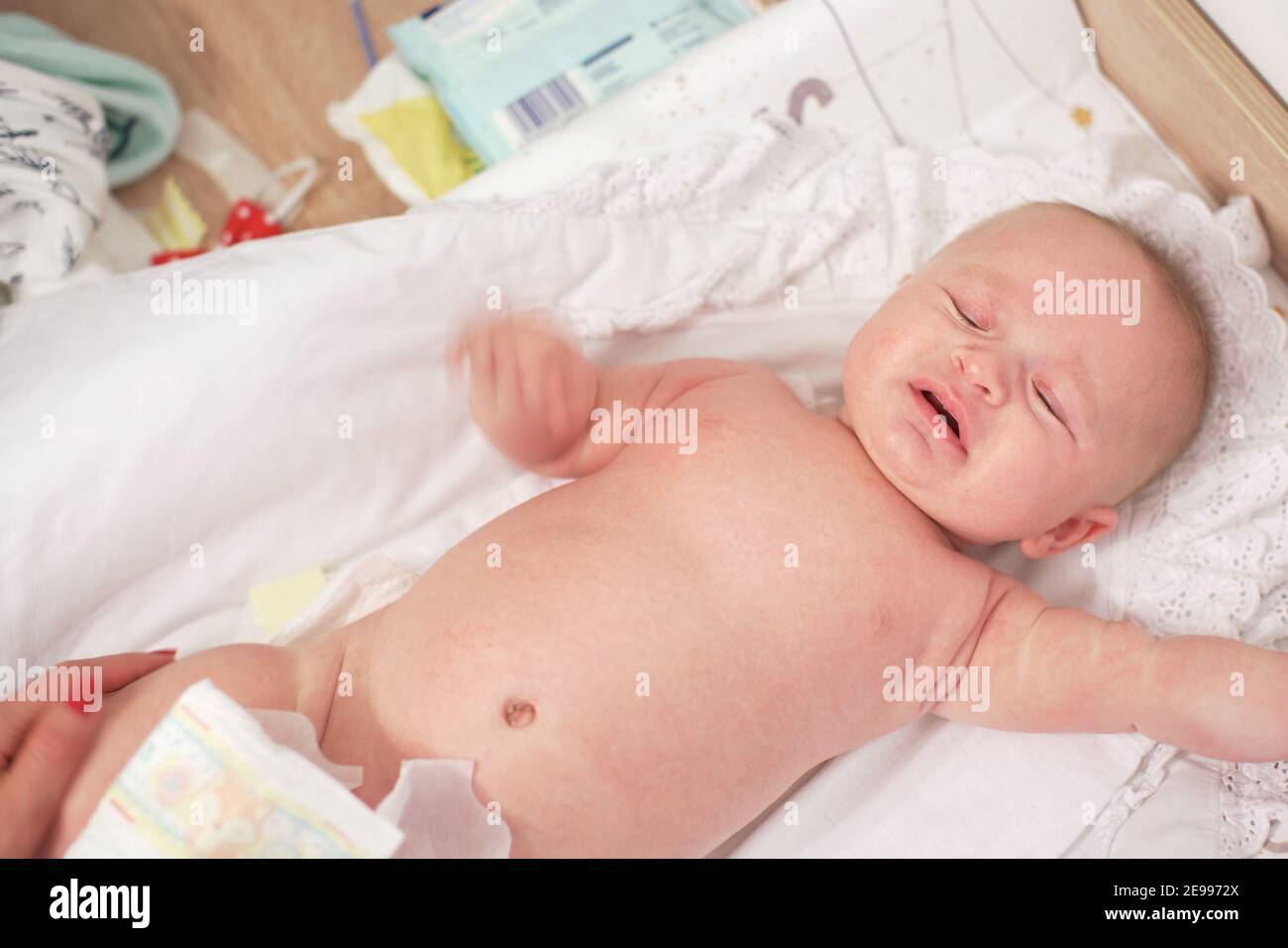 4 months old infant baby boy at changing table, looks like he's crying ...