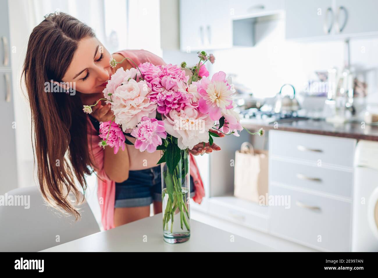 Valentine's day. Woman smelling bouquet of peonies at home. Housewife ...