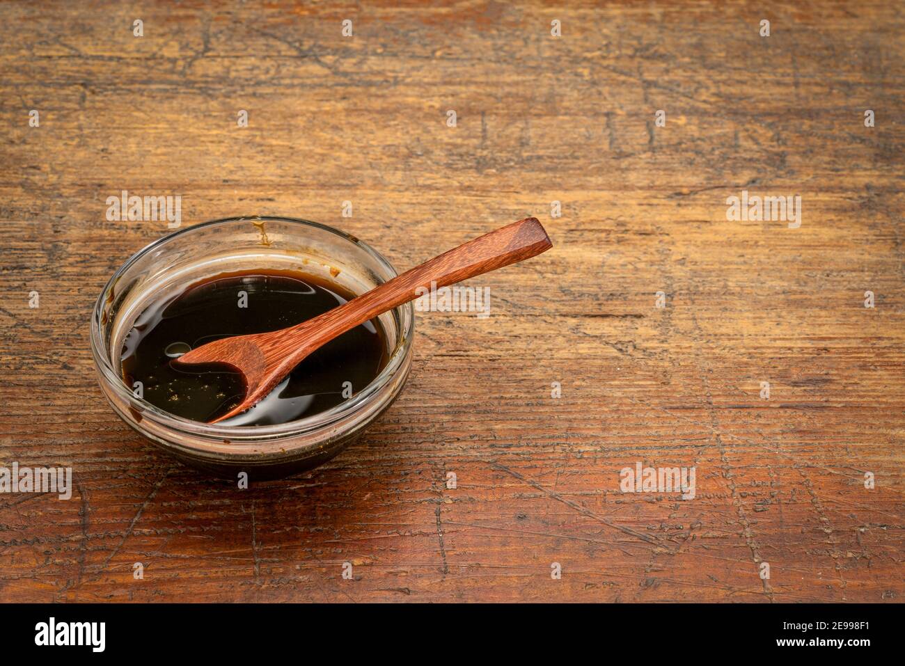 a small bowl of yacon syrup against rustic weathered wood, a powerful ...