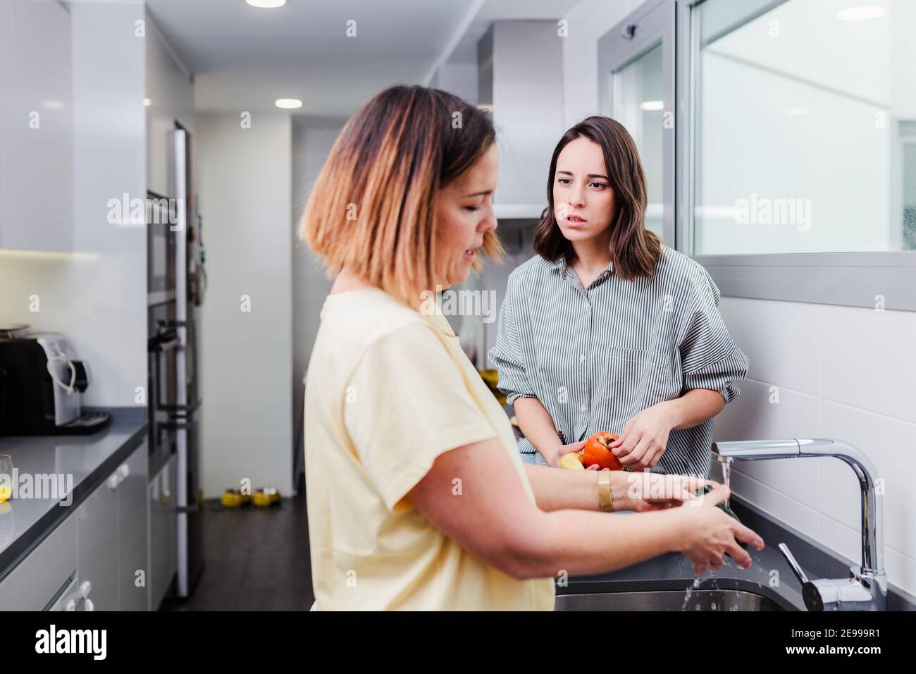 Women preparing healthy food and washing some vegetables in kitchen ...