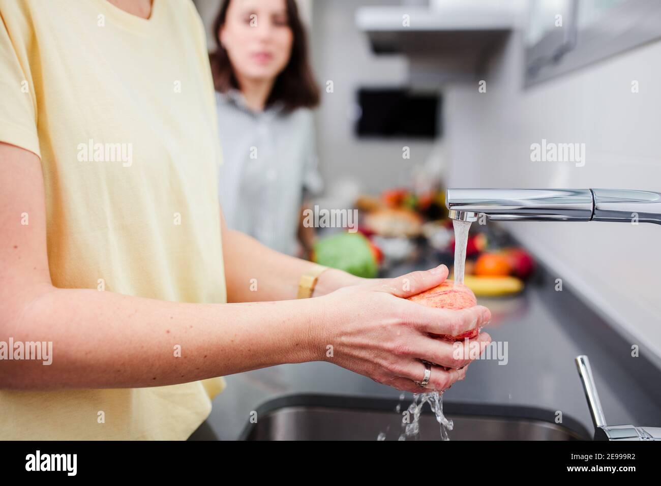 Women preparing healthy food and washing some vegetables in kitchen ...