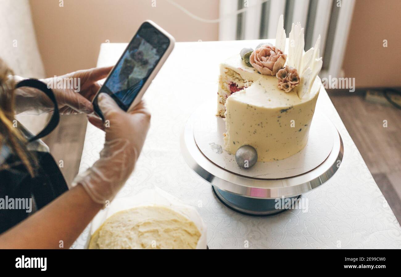 a young pastry chef girl takes pictures of a prepared cake Stock Photo ...
