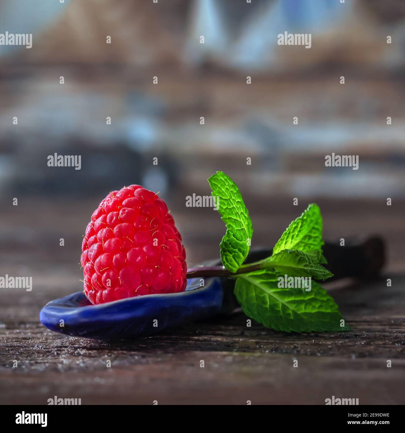 Ripe raspberry and mint leaf and ceramic spoon on an old brown wooden ...