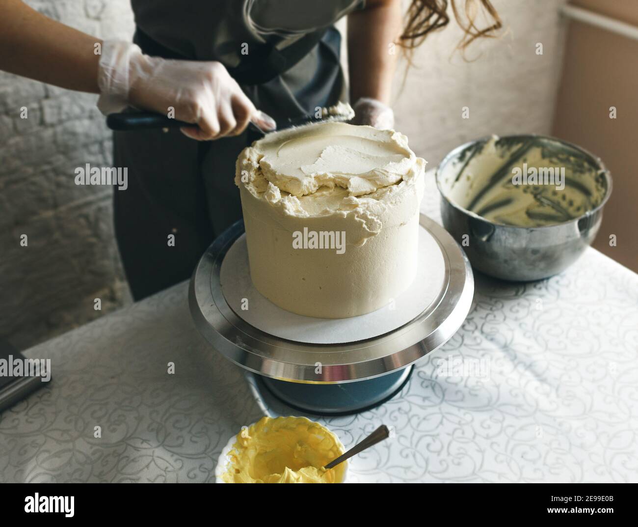 a pastry chef girl in a gray apron makes a cake in the kitchen Stock ...