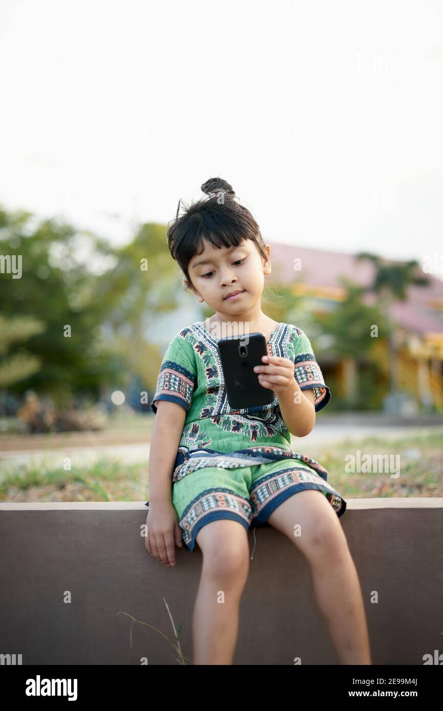 Little Girl studying online using smartphone at home front yard Stock ...