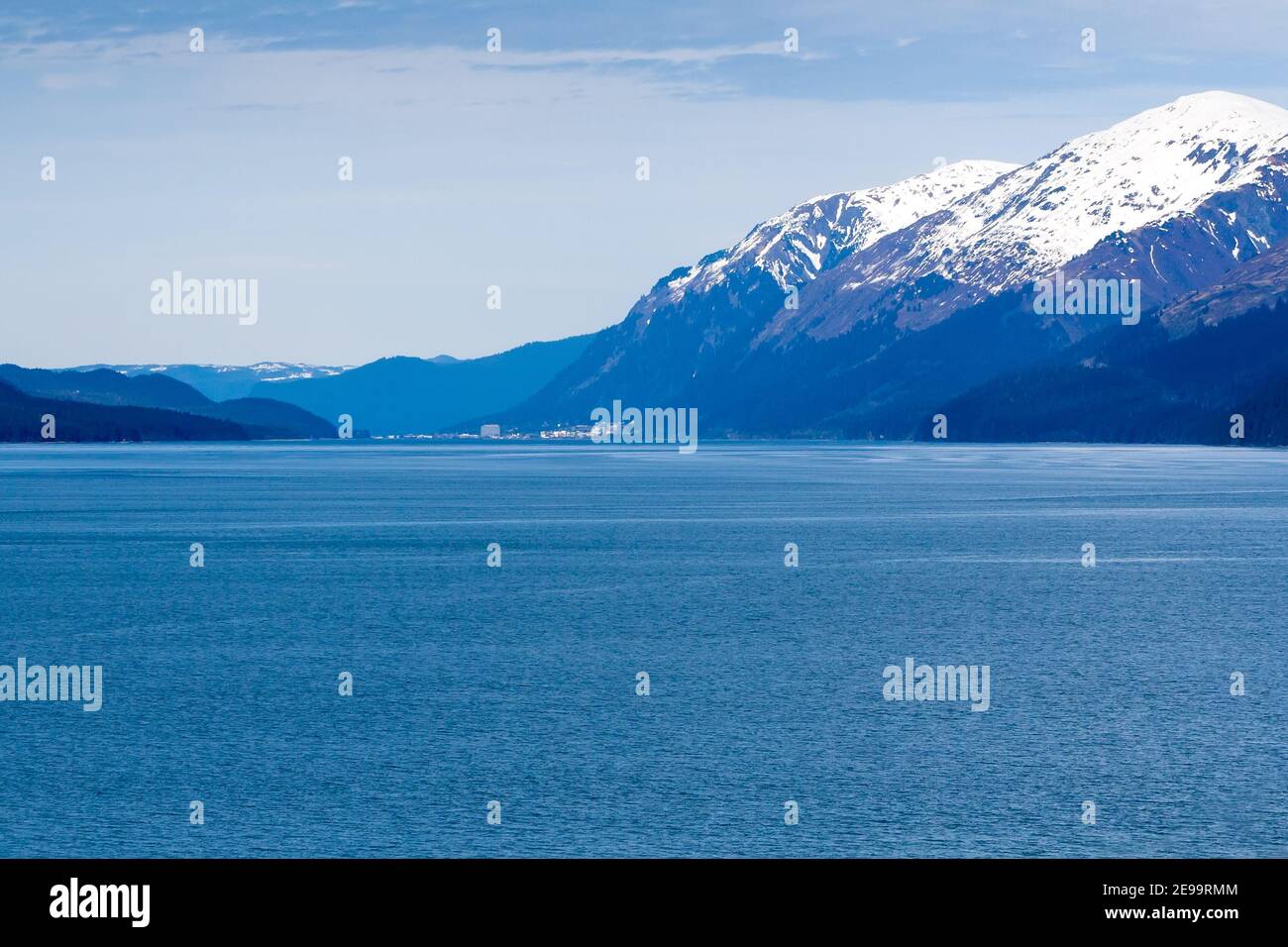 Snow-capped mountains and small town along the coast of southern Alaska ...