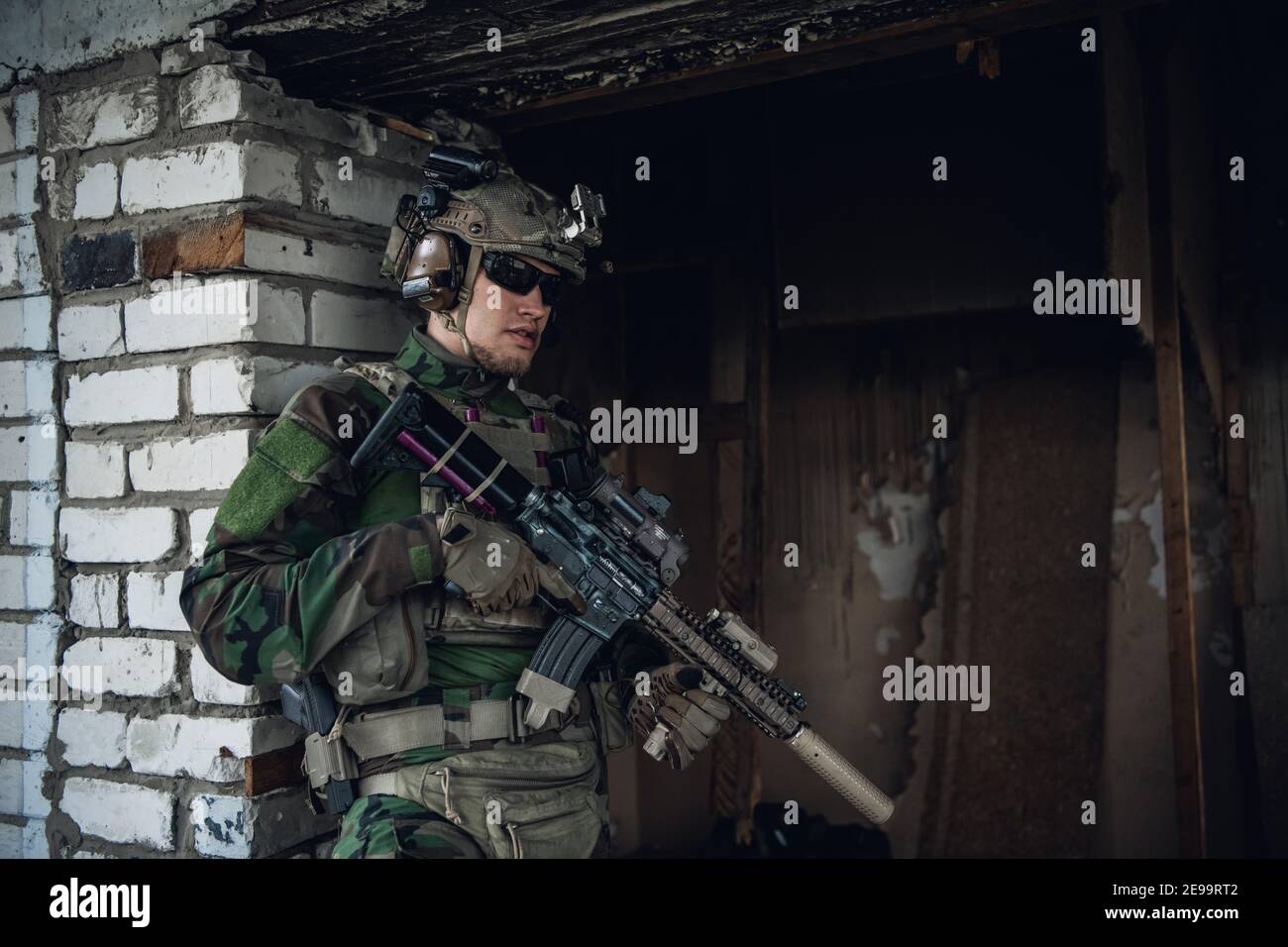 Military man with assault rifle standing inside building, he is ready ...