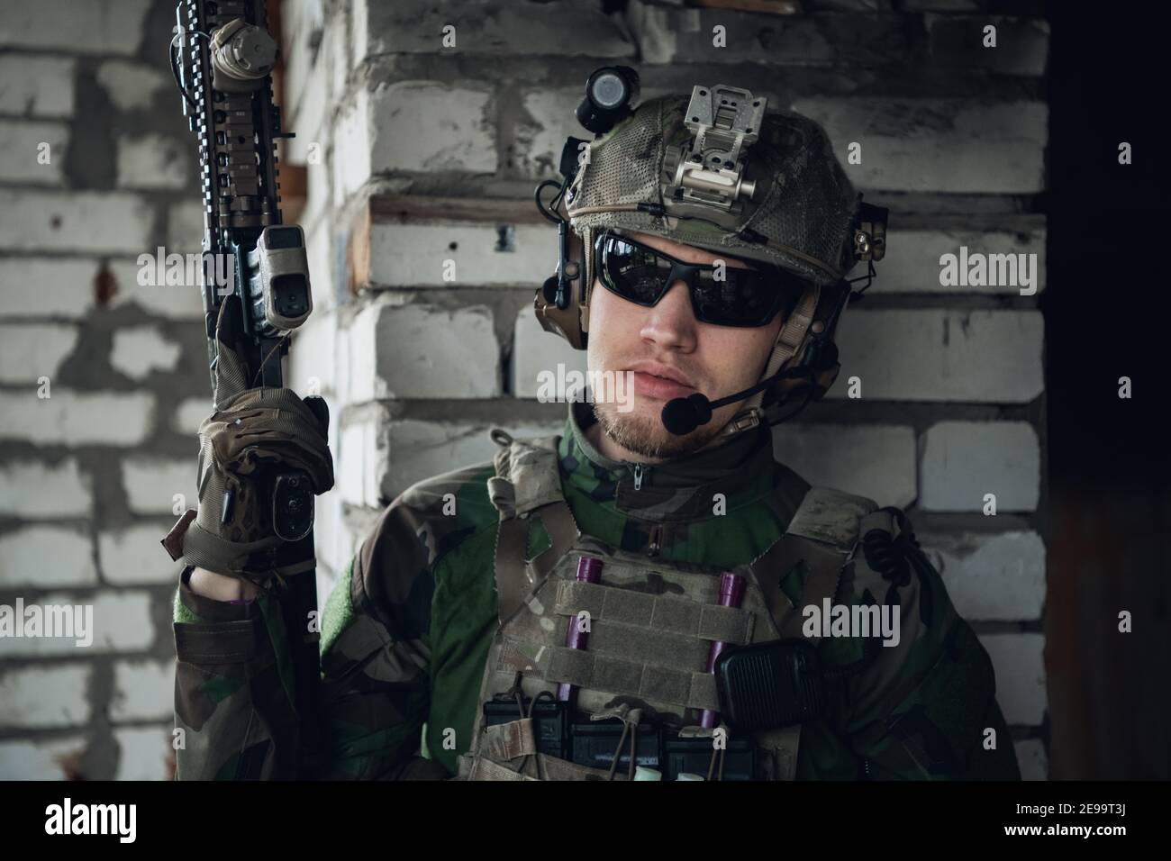 Military man with assault rifle standing inside building, he is ready ...