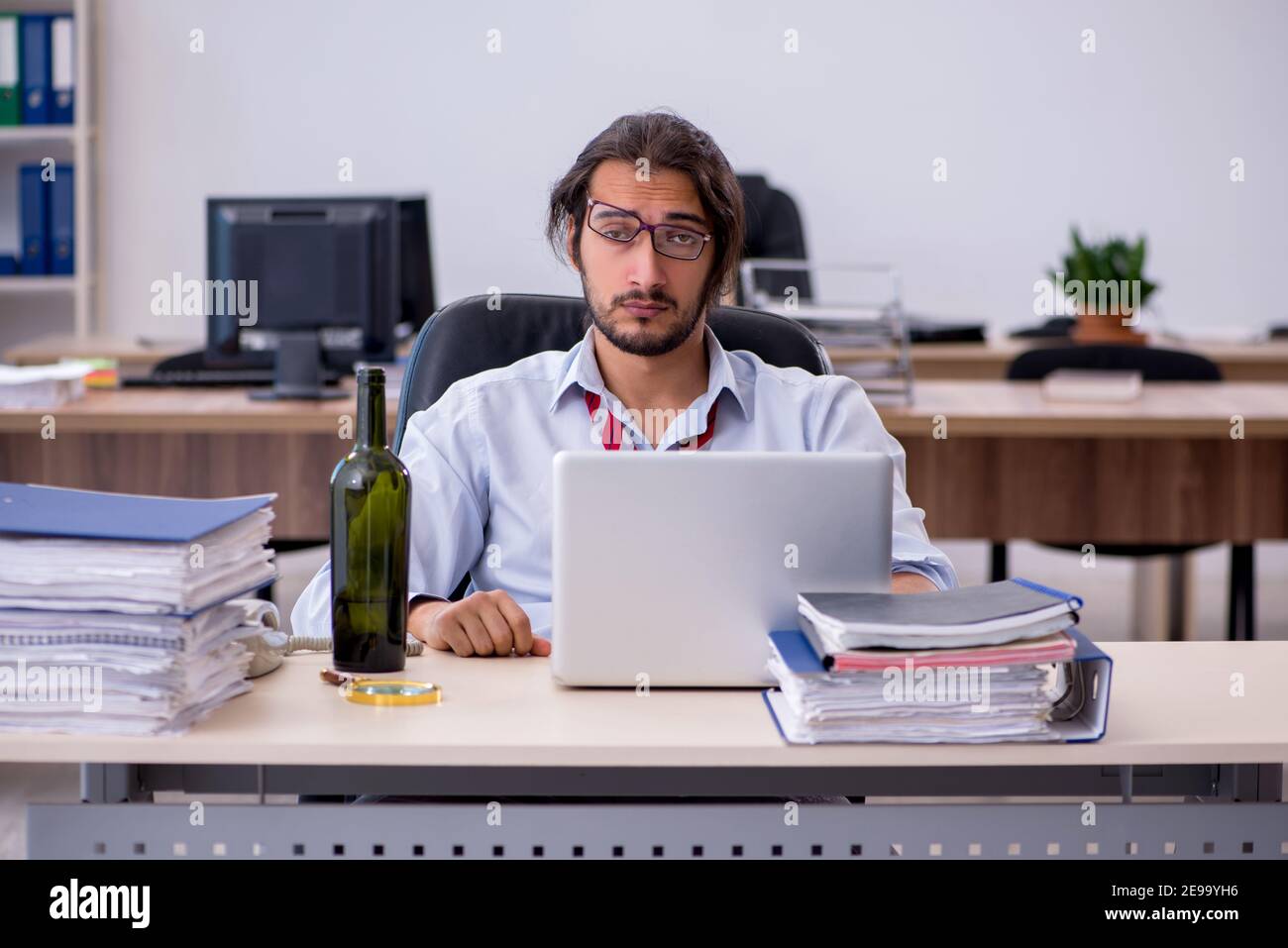 Young male employee drinking alcohol at workplace Stock Photo - Alamy