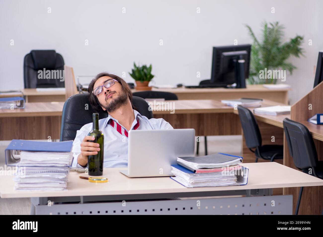 Young male employee drinking alcohol at workplace Stock Photo - Alamy