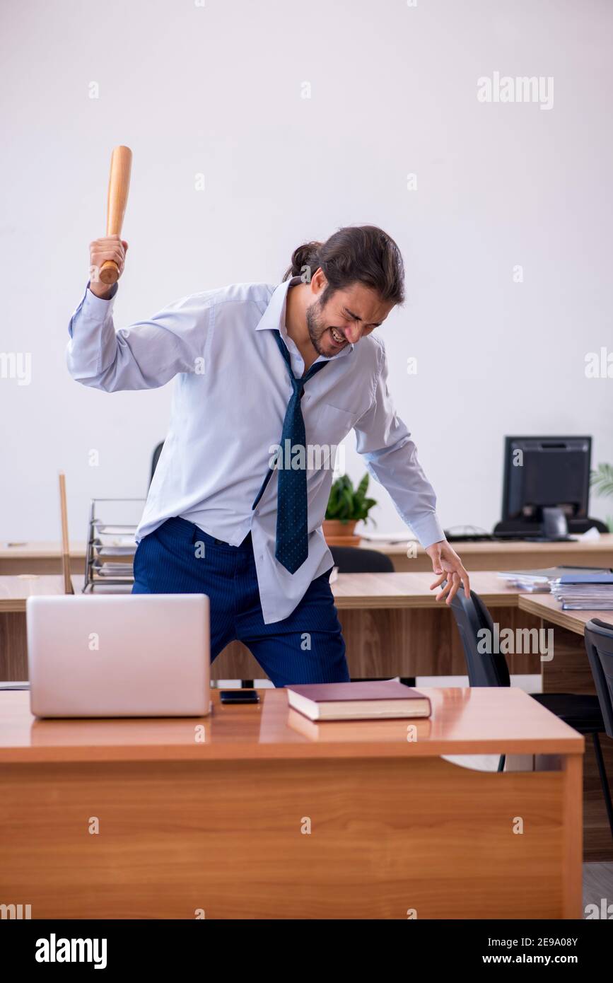 Young furious employee holding baseball bat in the office Stock Photo ...