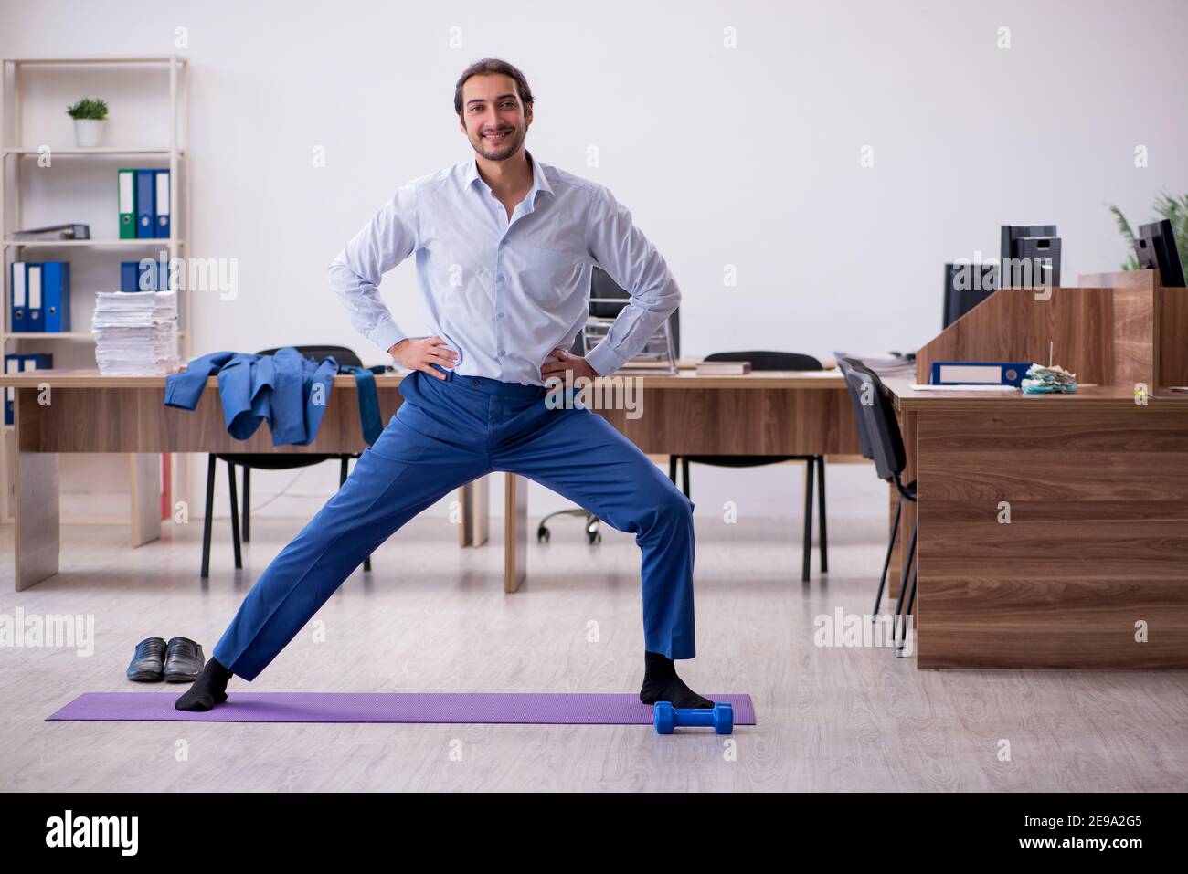 Young employee doing sport exercises during break Stock Photo - Alamy