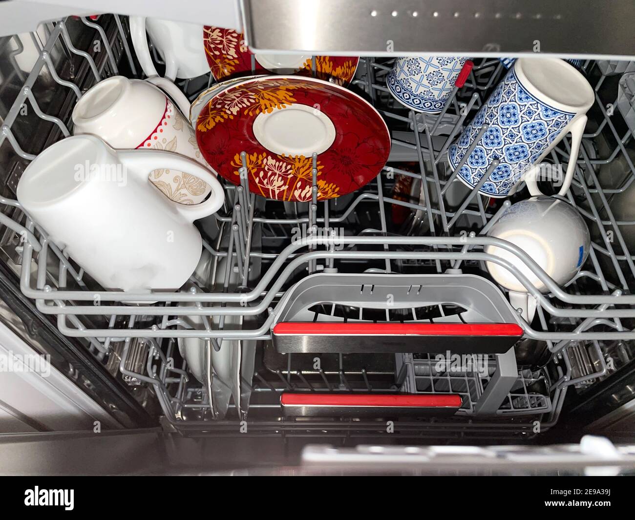 View inside the dishwasher with multiple plates and cups to be cleaned ...