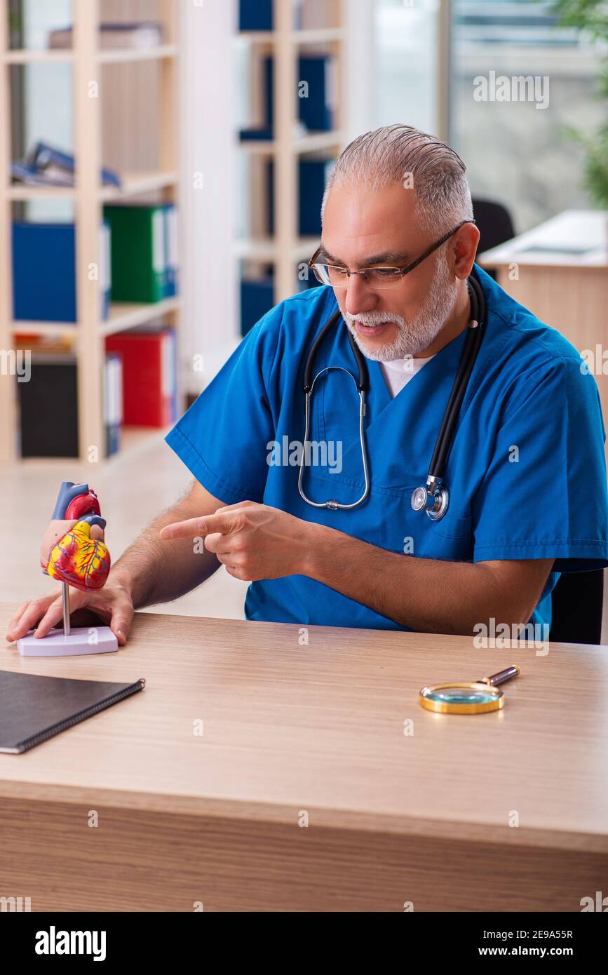 Old doctor cardiologist working in the clinic Stock Photo - Alamy