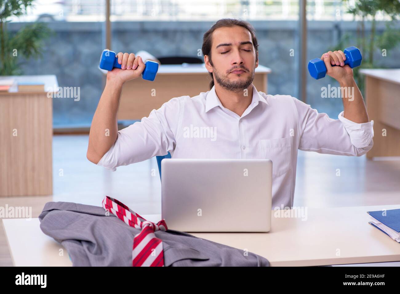 Young employee doing sport exercises at workplace Stock Photo - Alamy