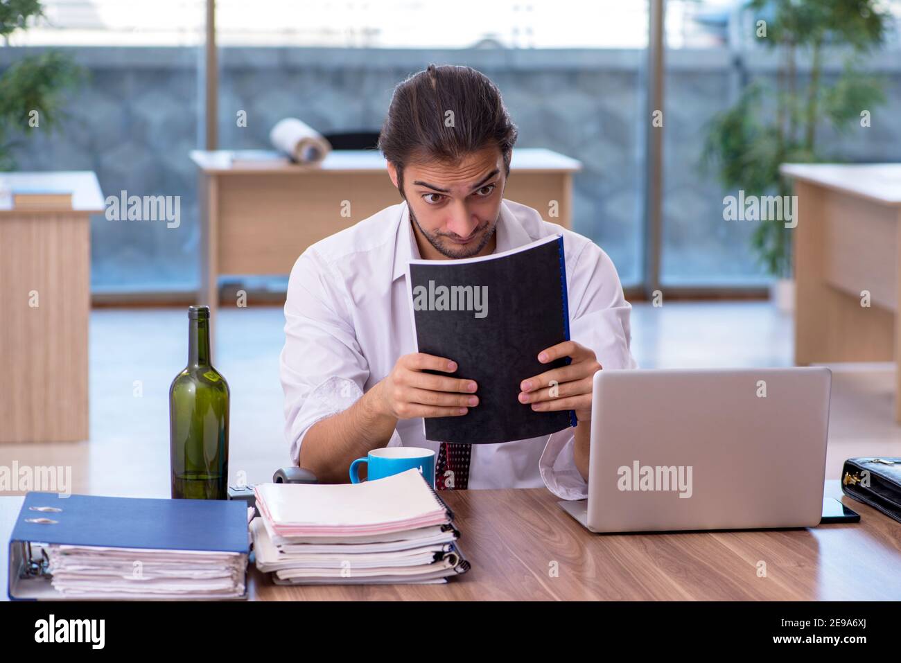 Young alcohol addicted employee working in the office Stock Photo - Alamy