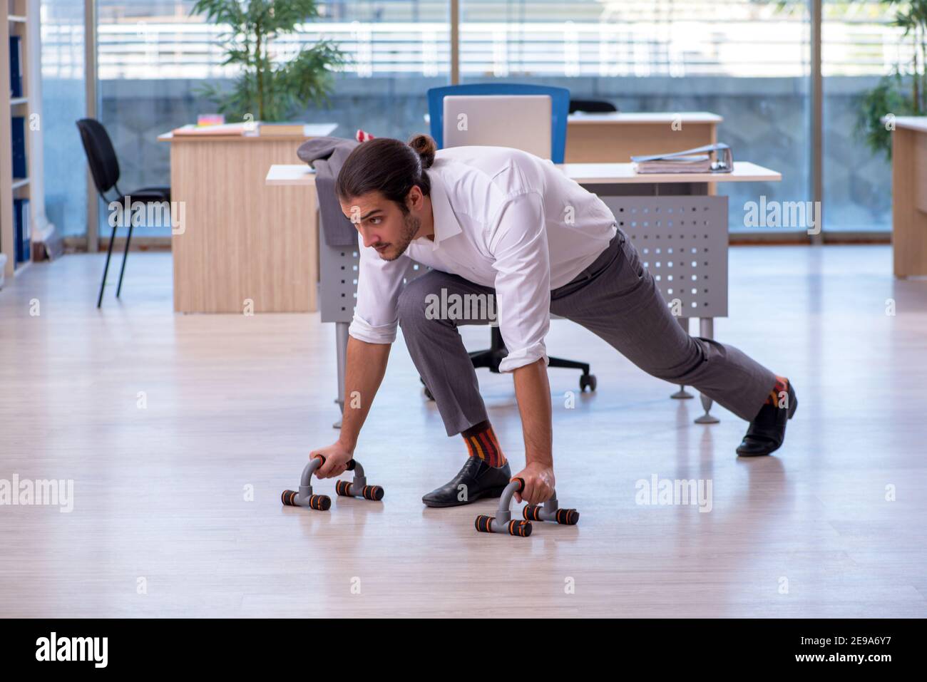 Young employee doing sport exercises at workplace Stock Photo - Alamy