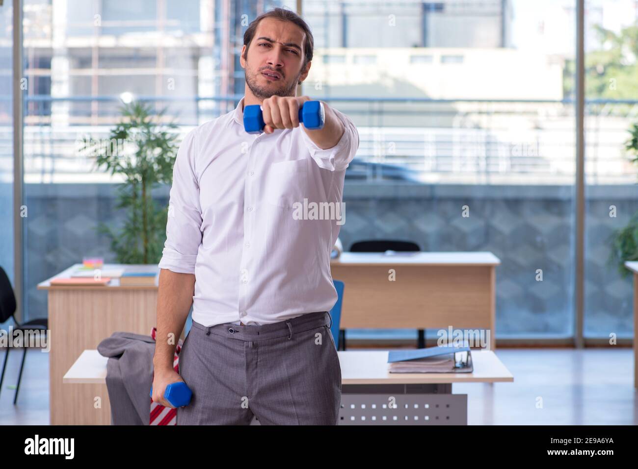 Young employee doing sport exercises at workplace Stock Photo - Alamy