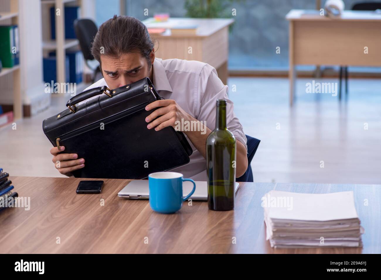 Young alcohol addicted employee working in the office Stock Photo - Alamy