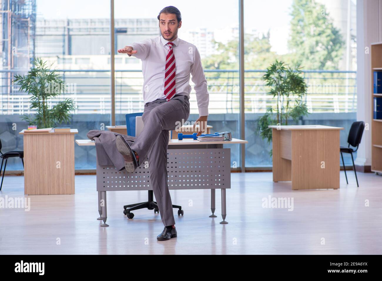 Young employee doing sport exercises at workplace Stock Photo - Alamy