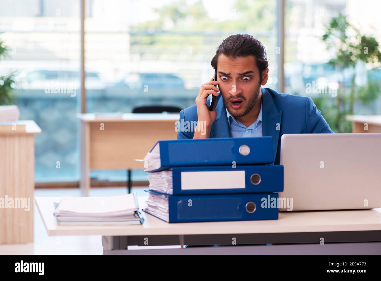 Young employee and too much work in the office Stock Photo - Alamy