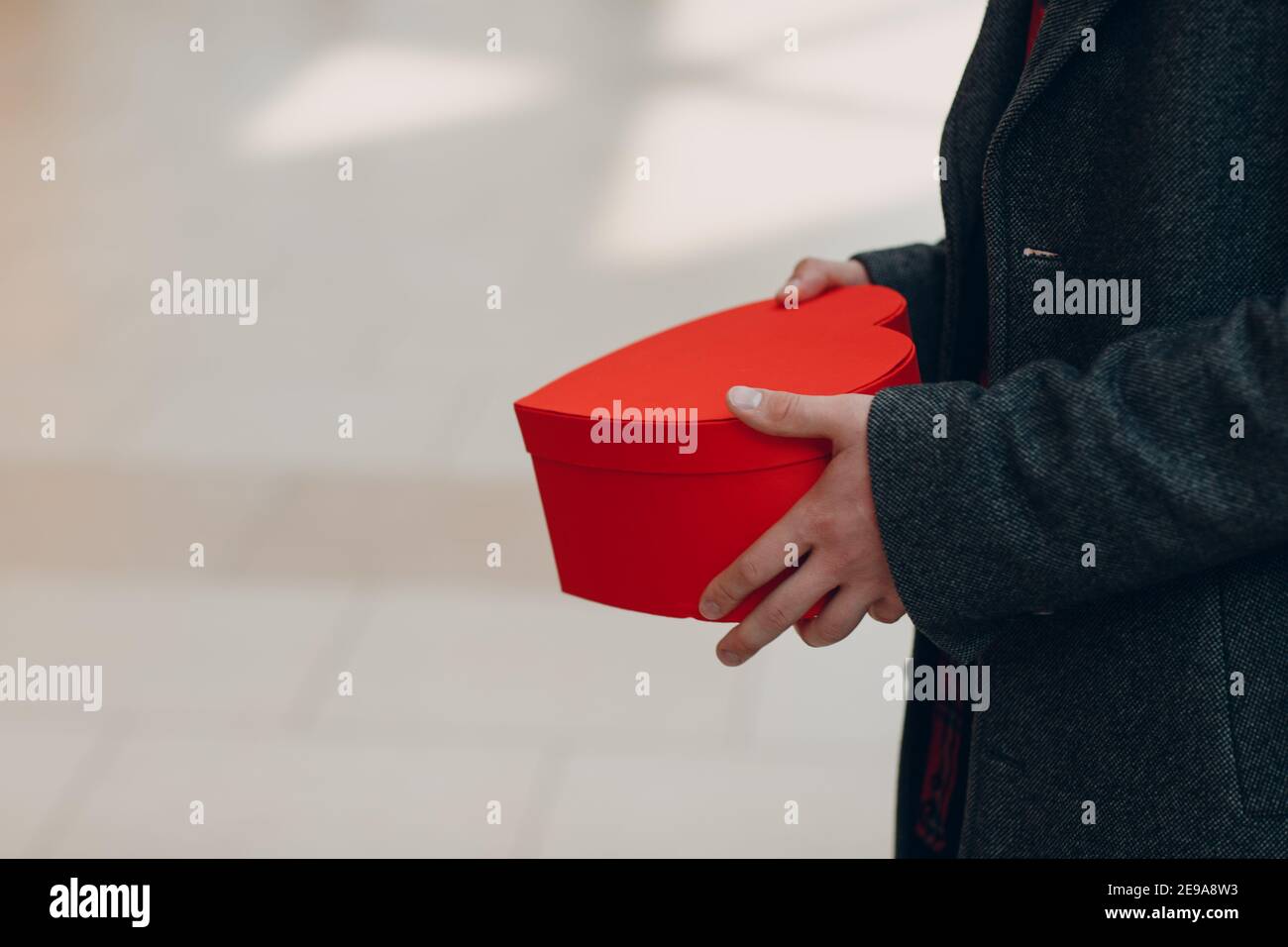 A guy holds heart-shaped box in Valentine's Day. Young man in shopping ...