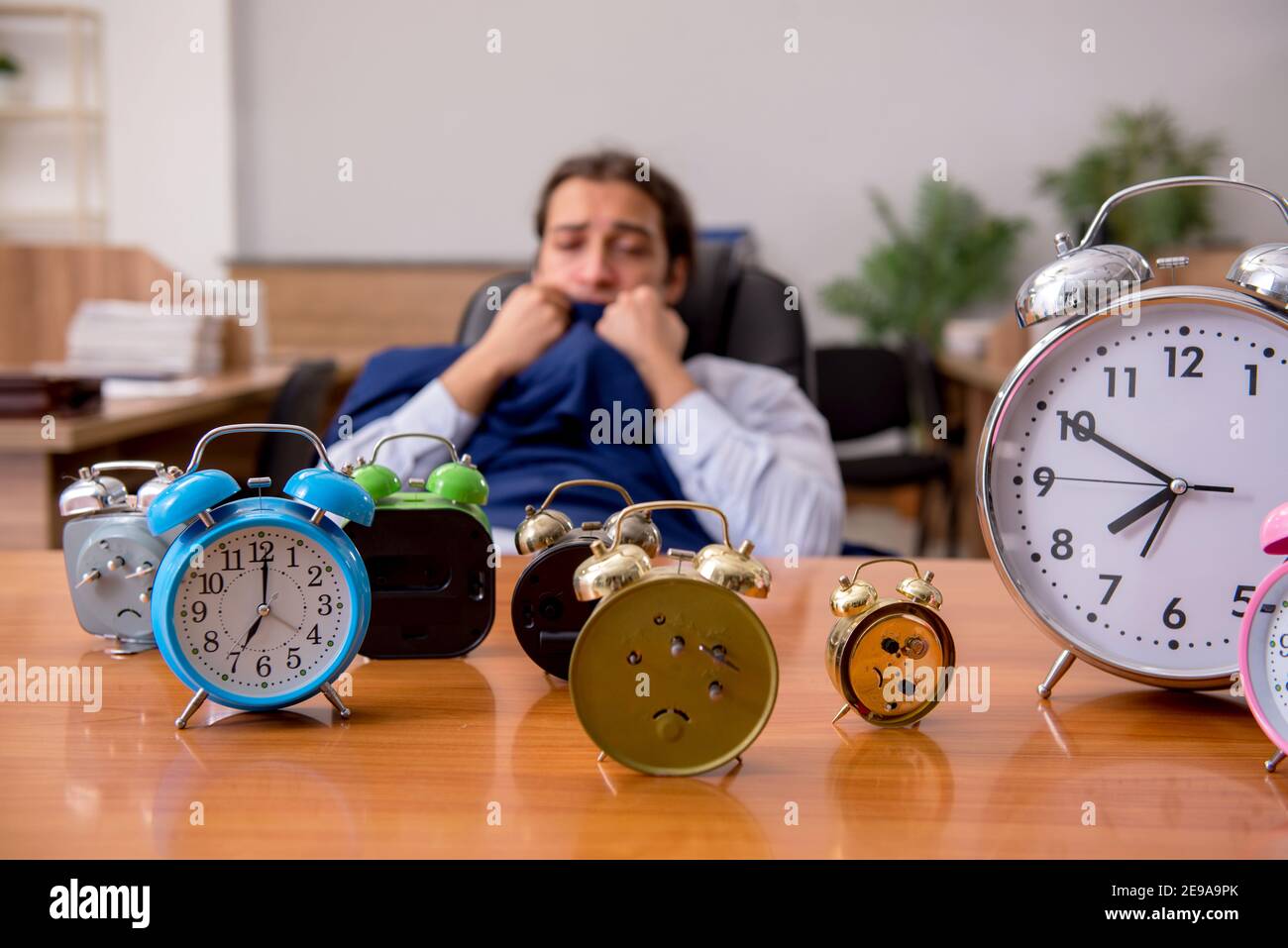 Young businessman sleeping in the office in time management concept ...