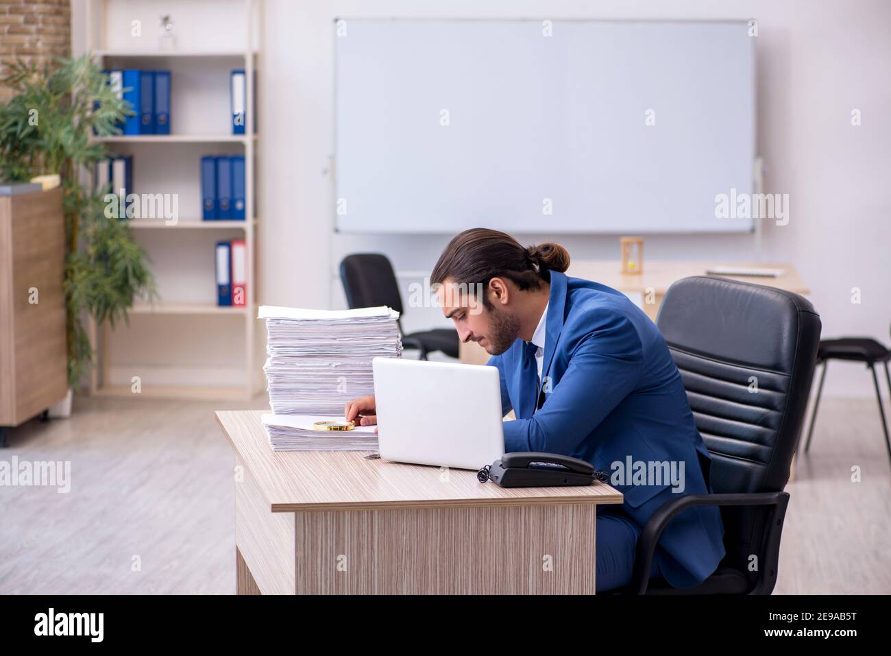 Young employee and too much work in the office Stock Photo - Alamy