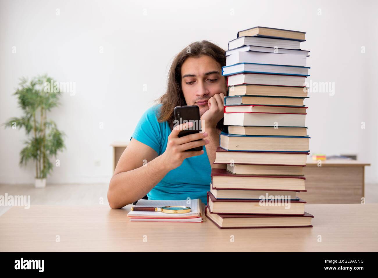 Young male student and a lot of books in the classroom Stock Photo - Alamy