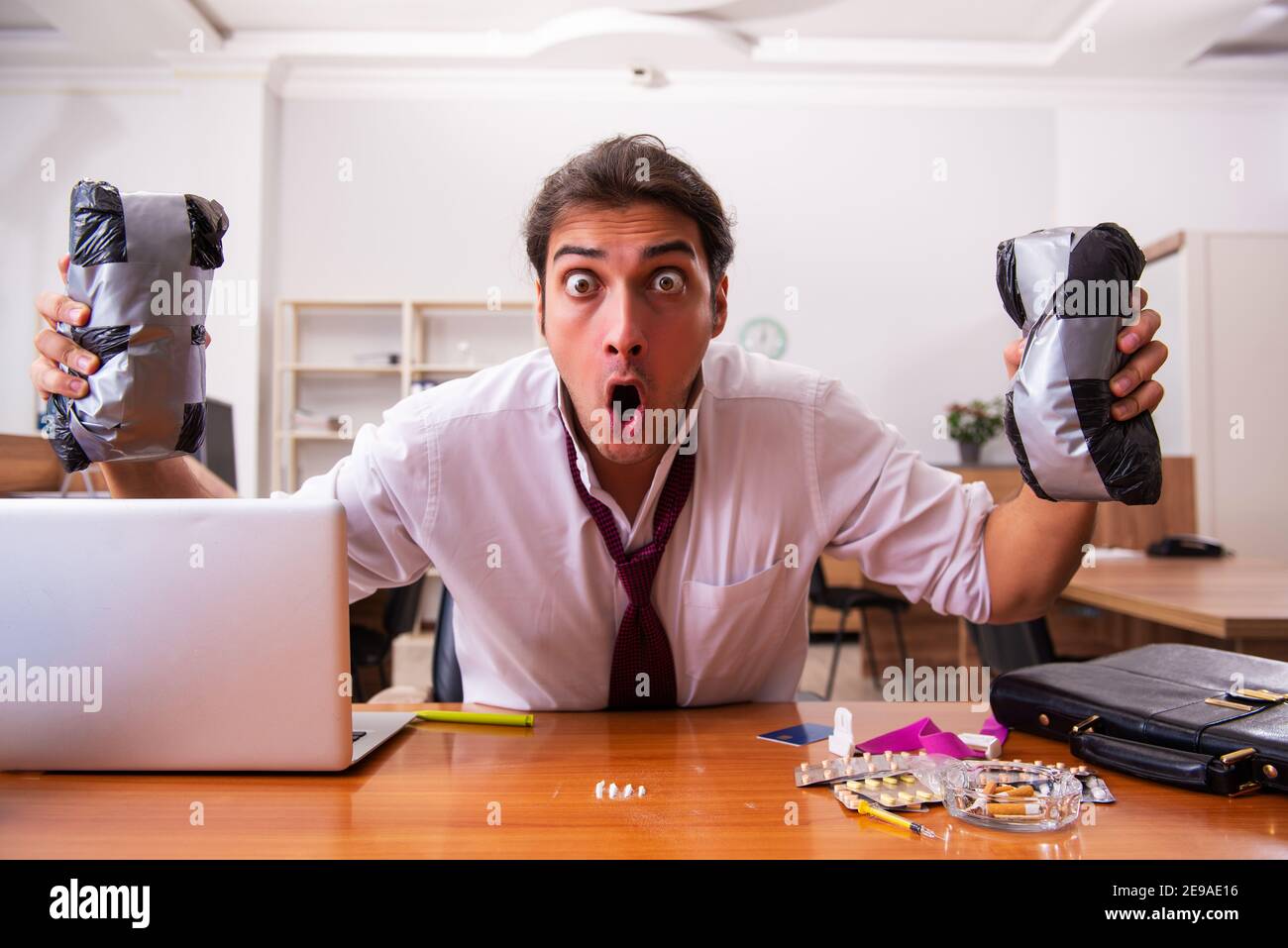 Young drug addicted male employee sitting at workplace Stock Photo - Alamy