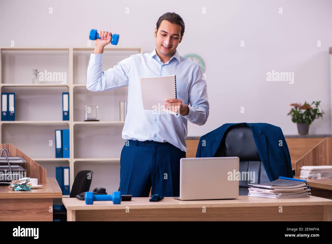 Young employee doing physical exercises at workplace Stock Photo - Alamy