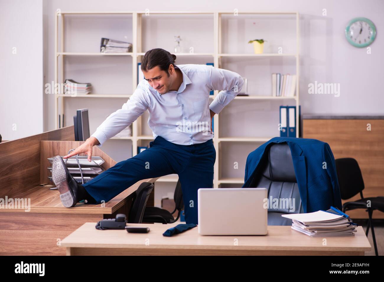 Young employee doing physical exercises at workplace Stock Photo - Alamy